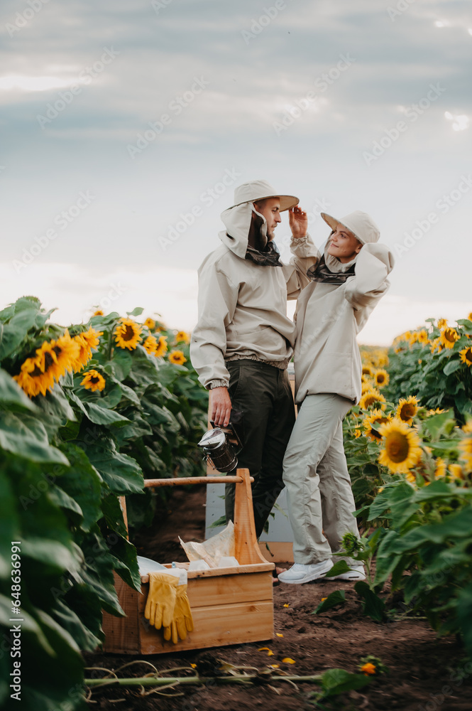 Young beekeepers work with bees in the apiary and eat honey.A young ...