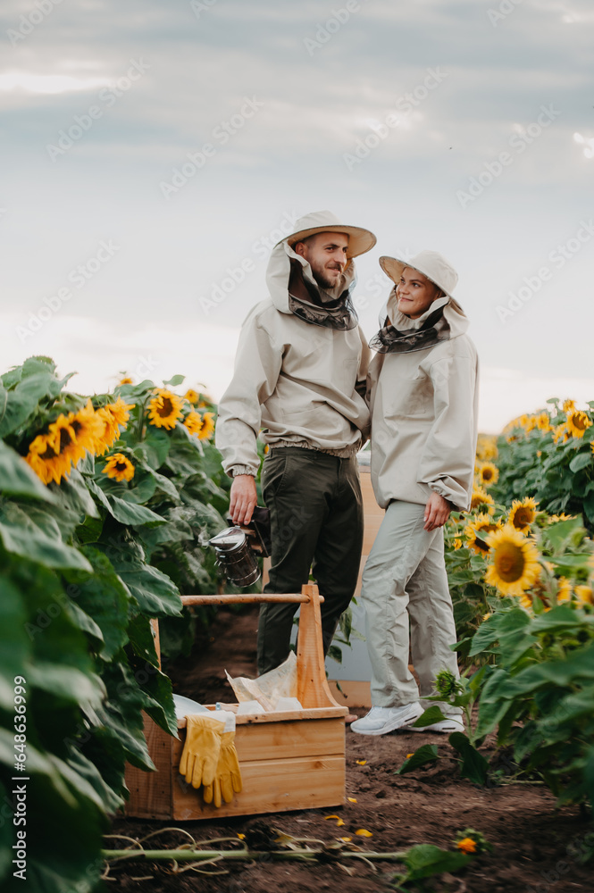Young beekeepers work with bees in the apiary and eat honey.A young ...