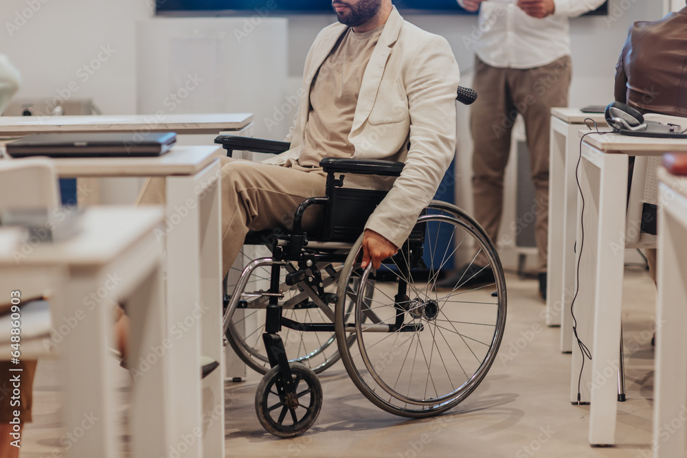 Handicapped man in wheelchair going back to his place at the classroom ...