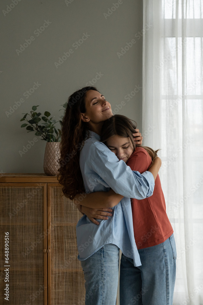 Young loving mother hugging her teenage daughter, mom demonstrating unconditional love for child ...