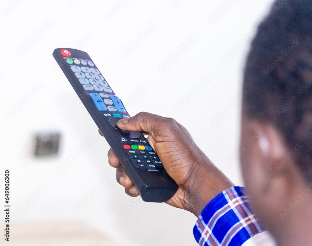 .An individual in a cozy setting, switching between news channels with ...