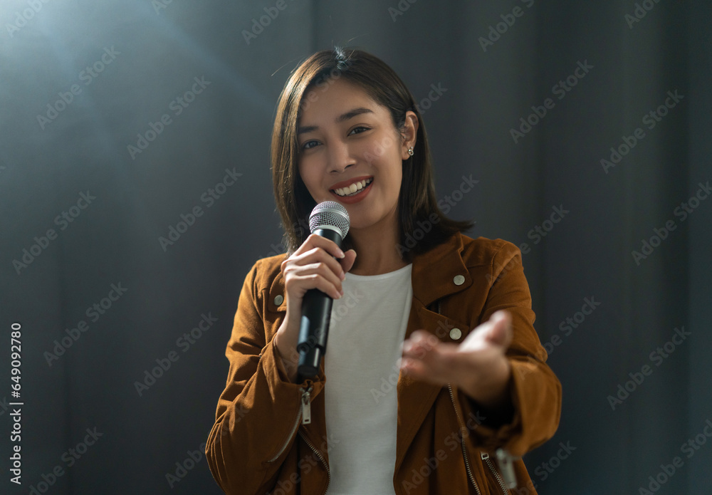 Attractive singer woman singing music on stage with spotlight strike ...