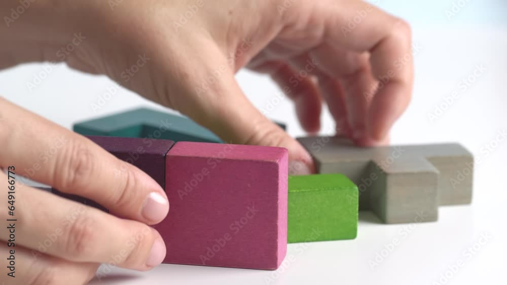 Female hand holding piece of wooden block puzzle. Wood cube stacking ...