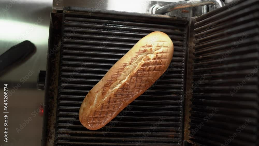 Close-up shot of hot dog bun laying on grate of an electric grill ...