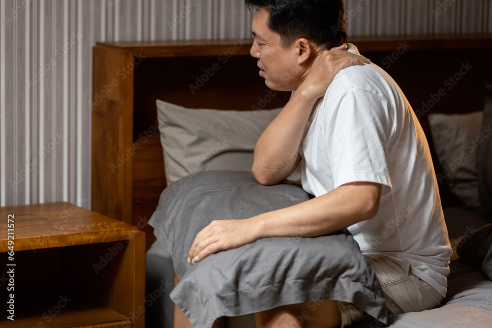 Asian middle aged man having neck muscle pain,sitting in bed,discomfort ...