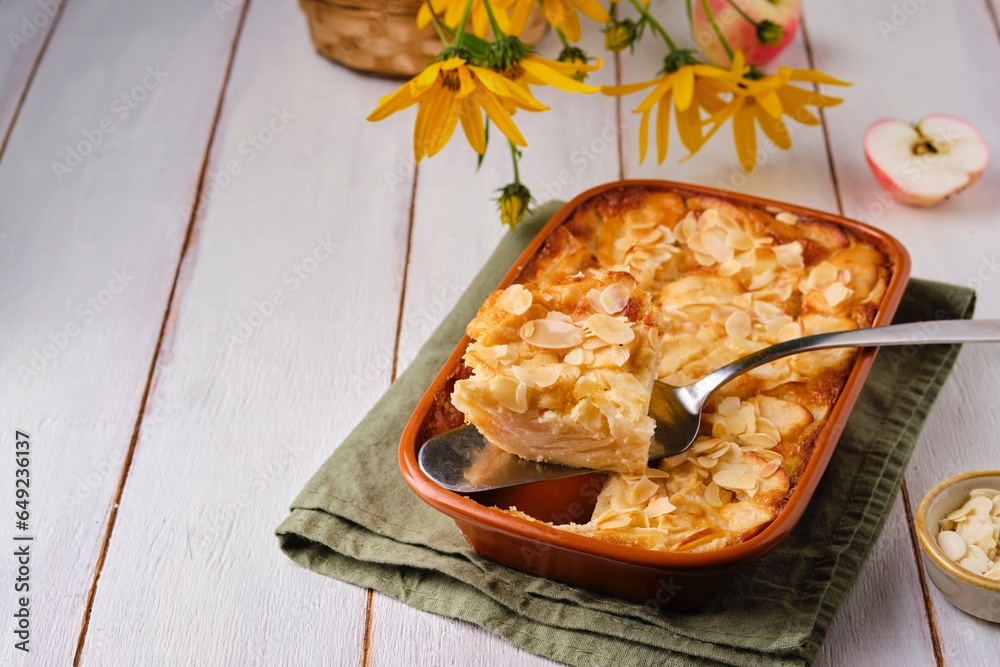 French apple pie, sprinkled with almond petals, in a rectangular brown ...