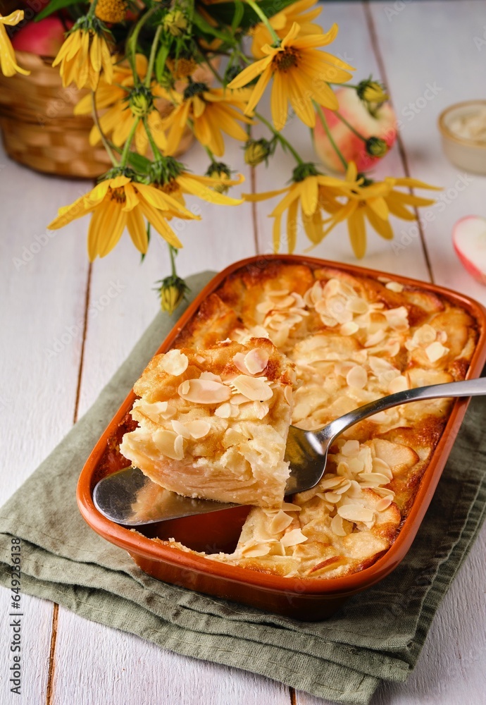 French apple pie, sprinkled with almond petals, in a rectangular brown ...