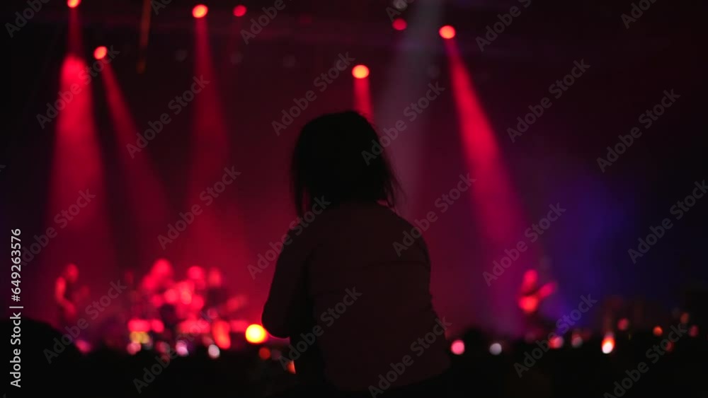 Happy little girl sit on her dad. Small kid have fun live music concert ...