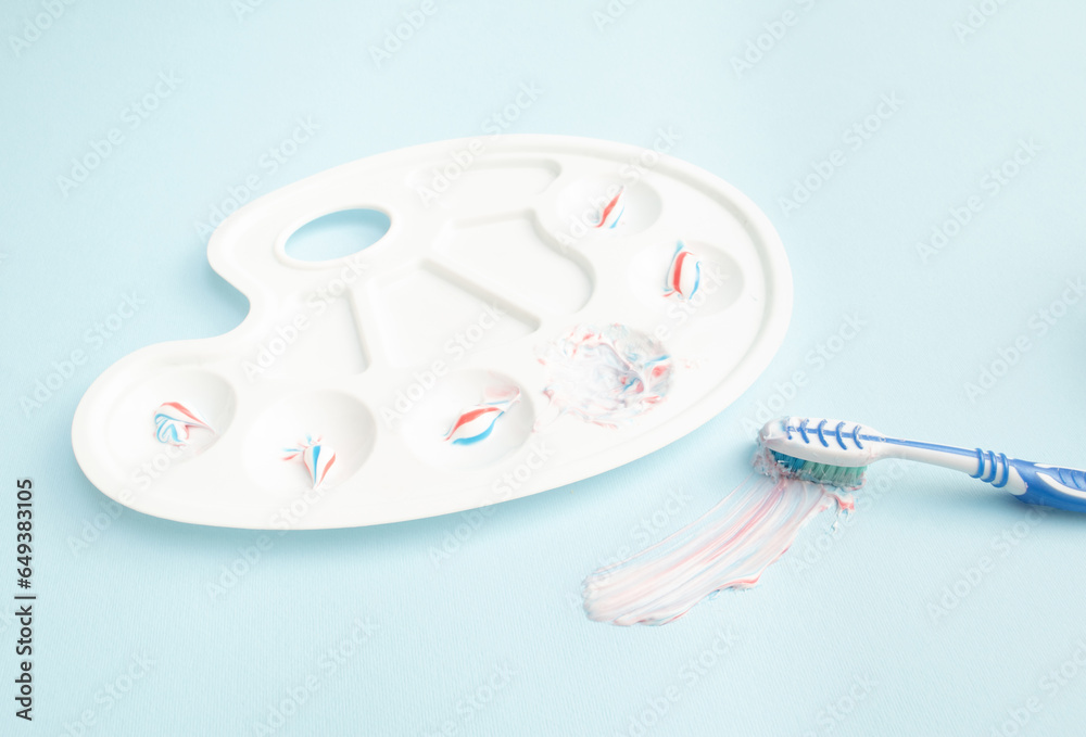 Painting palette with a dentifrice on a pastel blue background. A ...