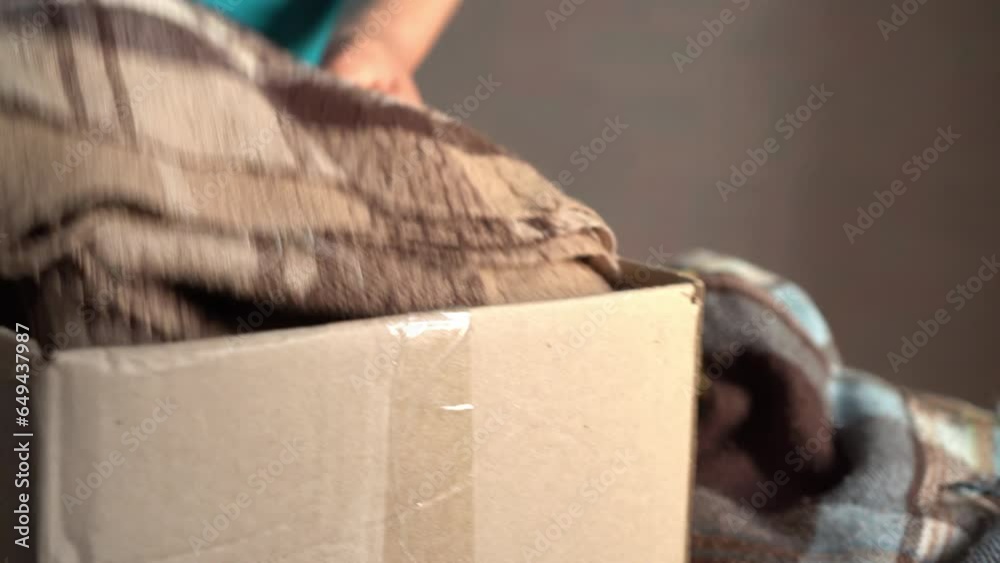Volunteer stacking warm plaid blankets in a donation box. Woman donates ...