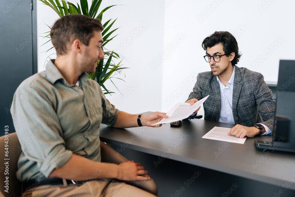 Smiling male job applicant arrives at interview, giving resume to ...