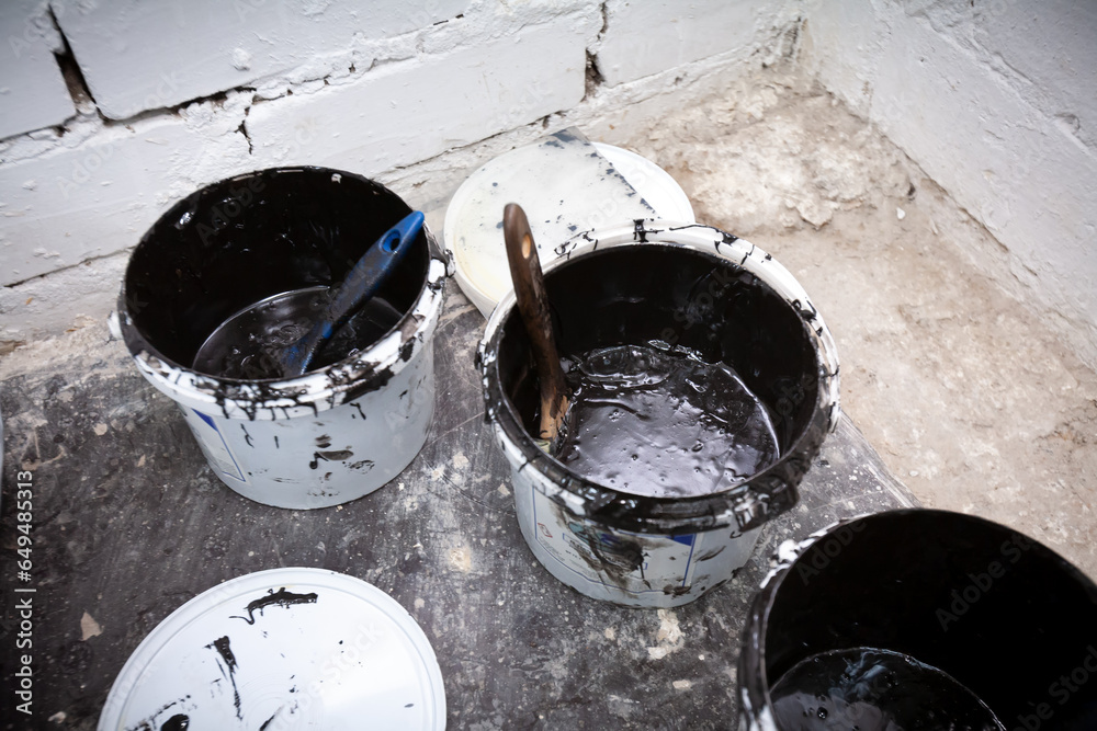 Workers at a repair company mix two-component black epoxy resin for a ...