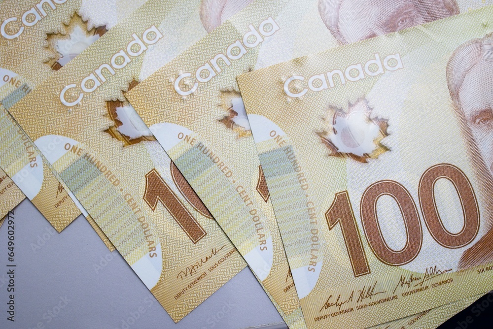 Canadian 100 dollars banknotes laid out on a table. $100 dollar bills ...
