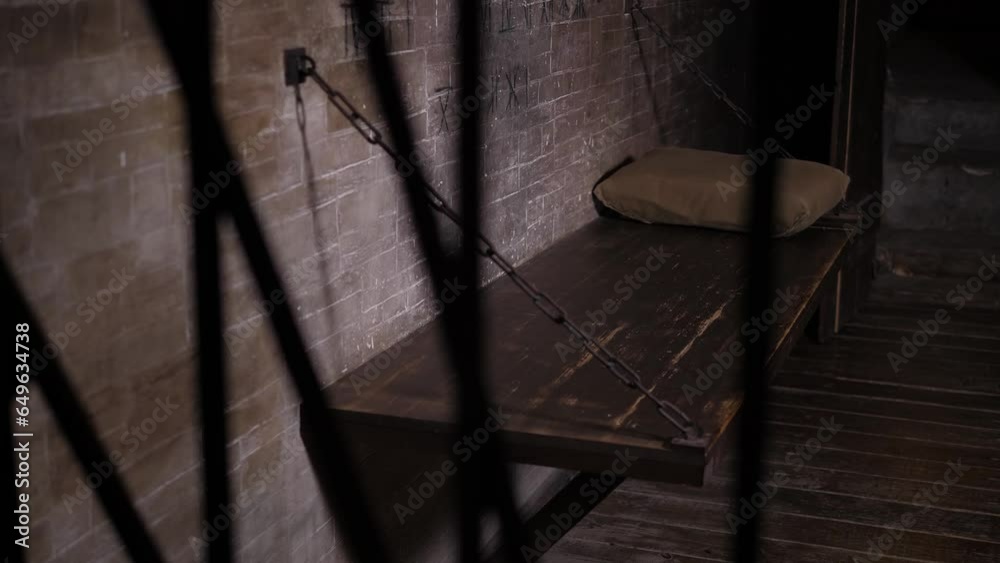 Stockvideon An old prison cell with a wooden bed and a pillow, a metal ...