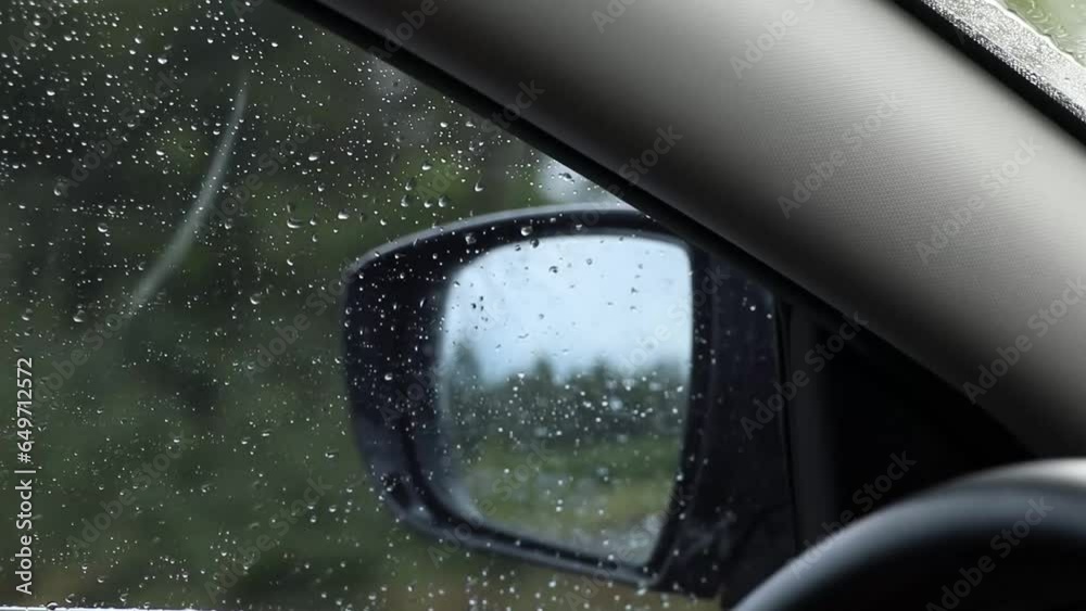 Rain outside the car window, view in the rearview mirror from a car at ...
