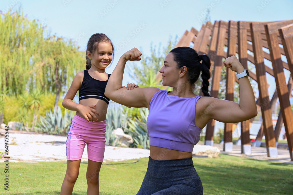 Super mom flexing her powerful bicep with her daughter. Sporty mother ...