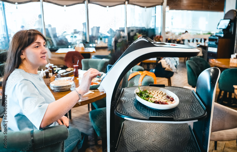 Robot waiter serve food at modern restaurant table.Offering innovation ...