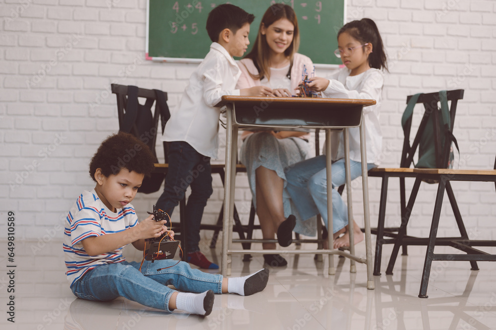 A teacher is teaching a group of children to sit and assemble robots ...