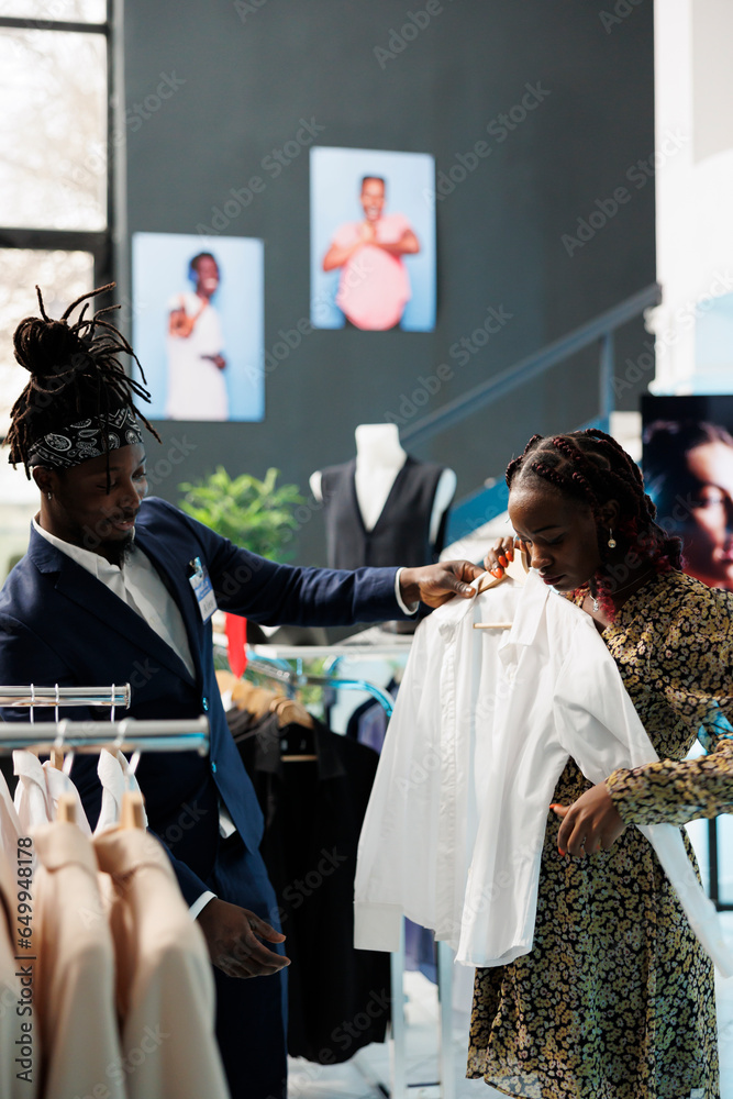 Boutique worker helping client with formal wear, looking at white shirt ...