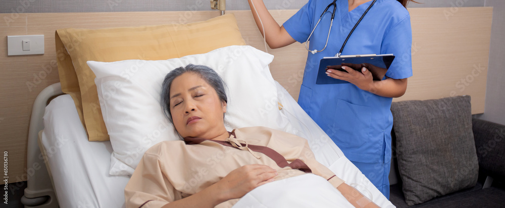 Asian nurse check saline and check patient elderly while asleep on bed at hospital ward, doctor ...
