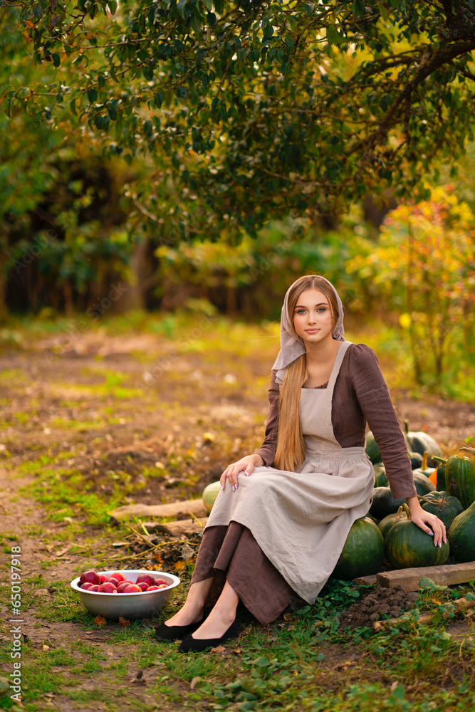 Beautiful young rural girl in medieval dress and bonnet hat posing on a ...