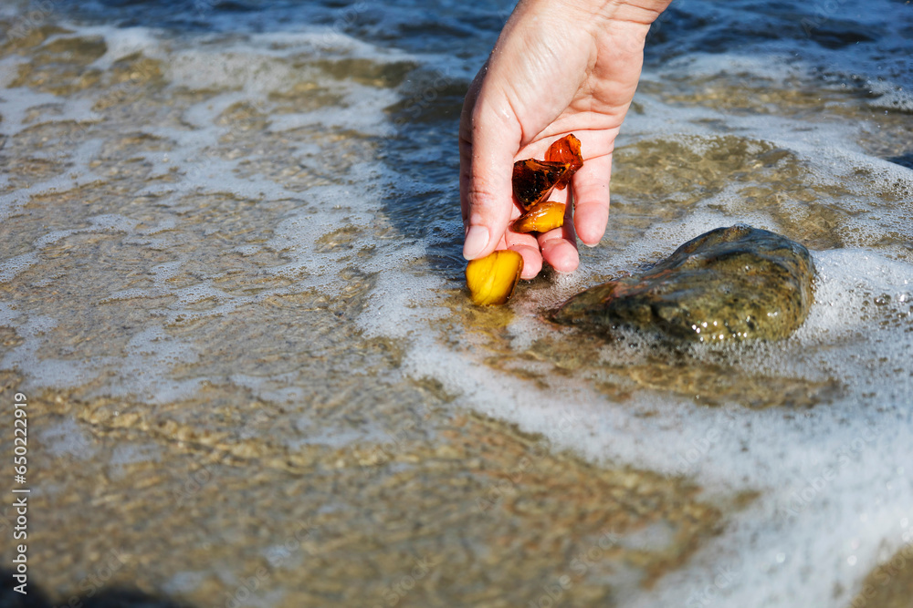 Beautiful pieces of amber in the hand of the sea background. A glowing ...