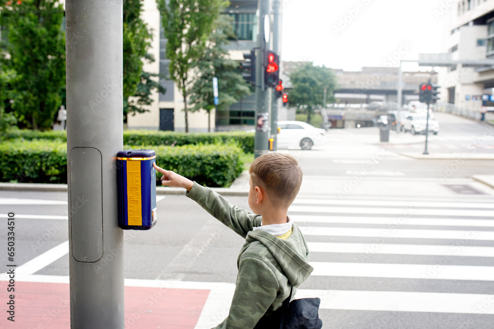 A child presses a traffic light button for pedestrians at a controlled ...