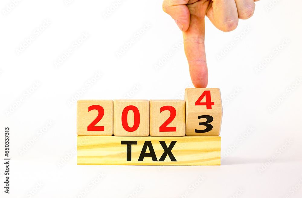 2024 tax new year symbol. Businessman turns a wooden cube and changes words Tax 2023 to Tax 2024 ...