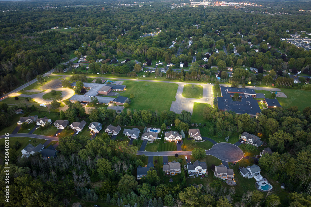 Upscale suburban homes at night with large backyards and green grassy ...