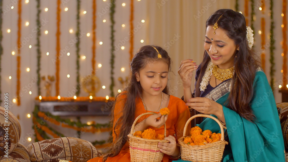 South Indian mother-daughter preparing flower garlands (mala) for ...