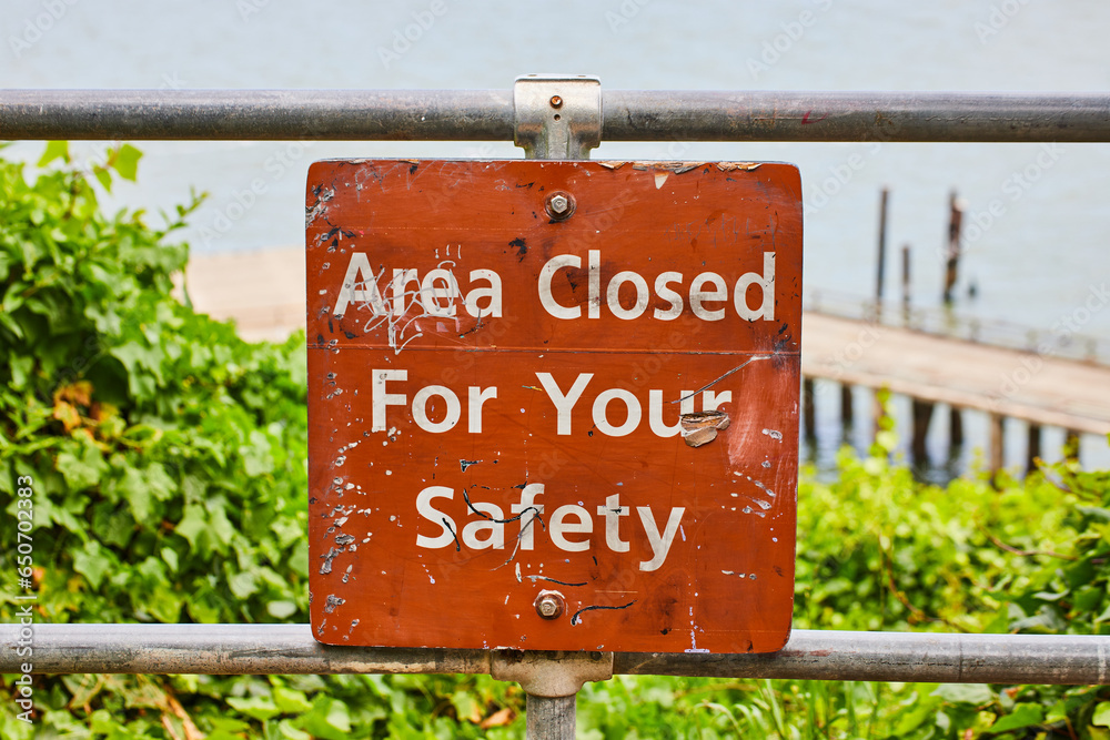 Orange Area Closed For Your Safety sign on metal railing with blurred ...