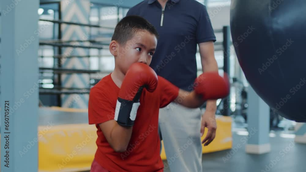 Young asian boy with a focused face in boxing gloves close up hitting ...