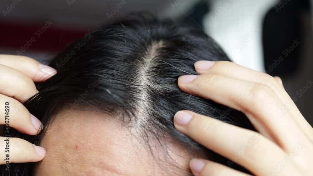 young woman examining her scalp and hair in mirror, hair roots, color ...