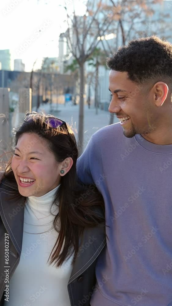 Happy diverse young friends walking together hugging each other outdoors. Multiethnic group of ...