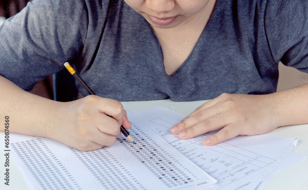Students hand holding pencil writing selected choice on answer sheets ...