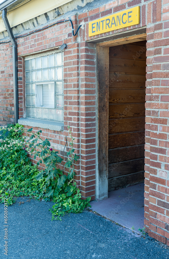 ENTRANCE sign above open door of red brick commercial building shows a ...