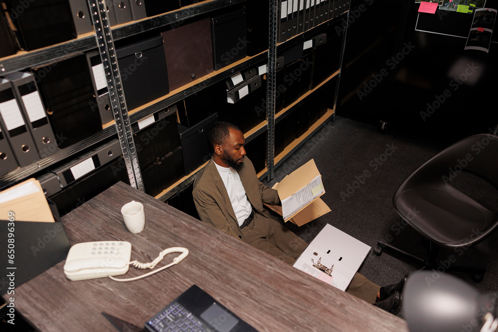 Overworked exhausted cop sitting on floor analyzing report in office ...