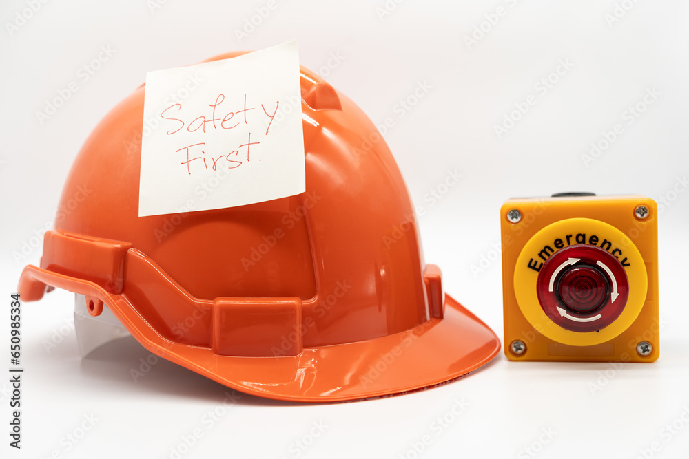 Orange safety hat with message Safety First and Emergency Stop Button ...