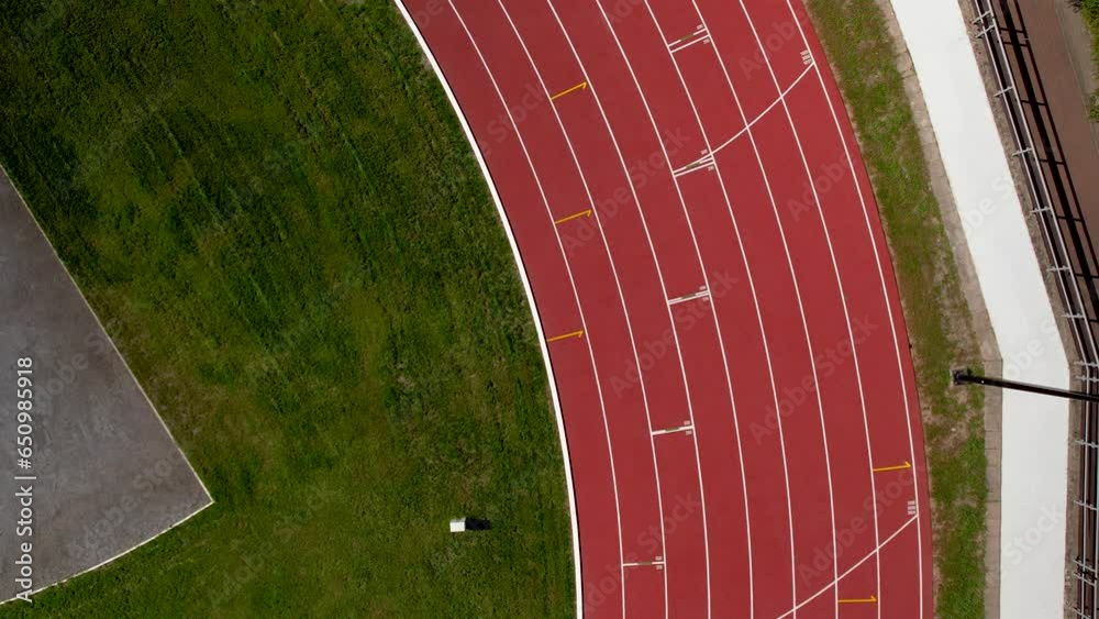 Zoom out top down aerial over the curve of the 100m finish line on a ...