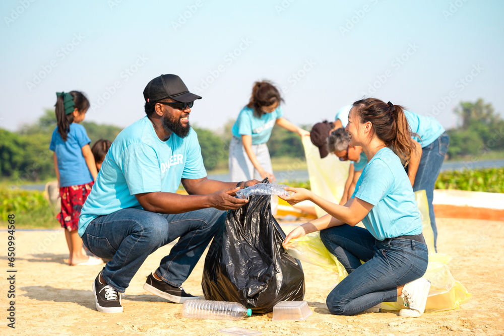 A diverse group of volunteers join together to cleanup the sand beach ...