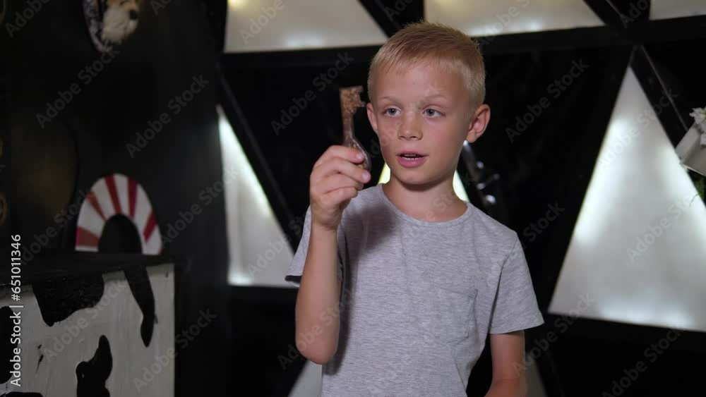 Portrait of an inquisitive boy with an old rusty key in a black and ...