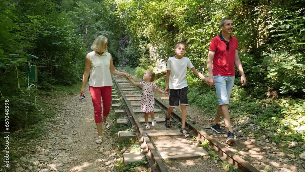 A happy family with children walk along the old narrow-gauge rails in ...