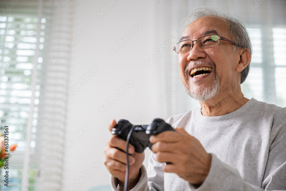 Asian senior old man enjoying holding joystick playing video game at ...