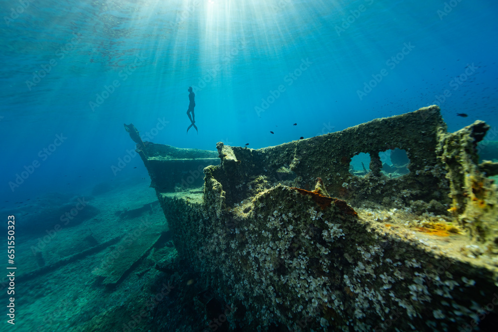 Freediver diving towards a shipwreck at the bottom of the sea. Young ...