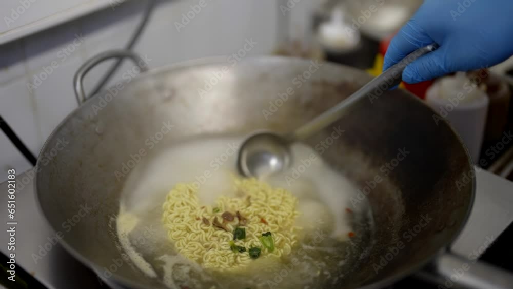 A professional chef cooks noodles. The cooking process is a close-up ...