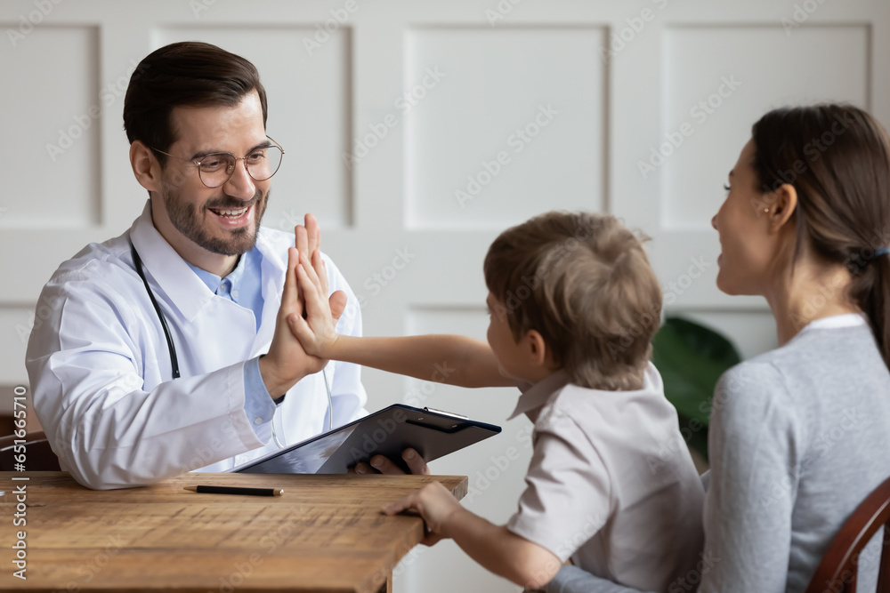 Smiling male pediatrician giving high five to little patient ...