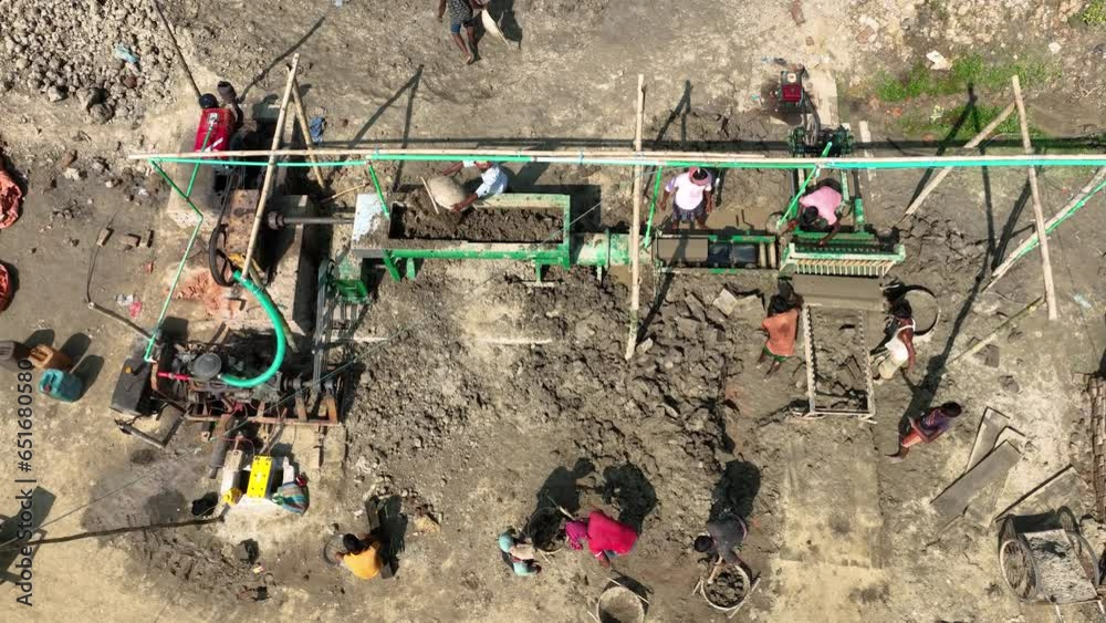 Workers in a brickfield or brick factory, making bricks from mud. The ...