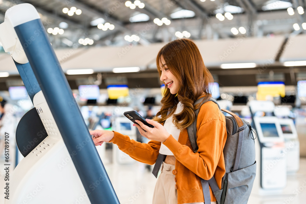 Young Asian woman using self check-in kiosks in airport terminal. Happy ...