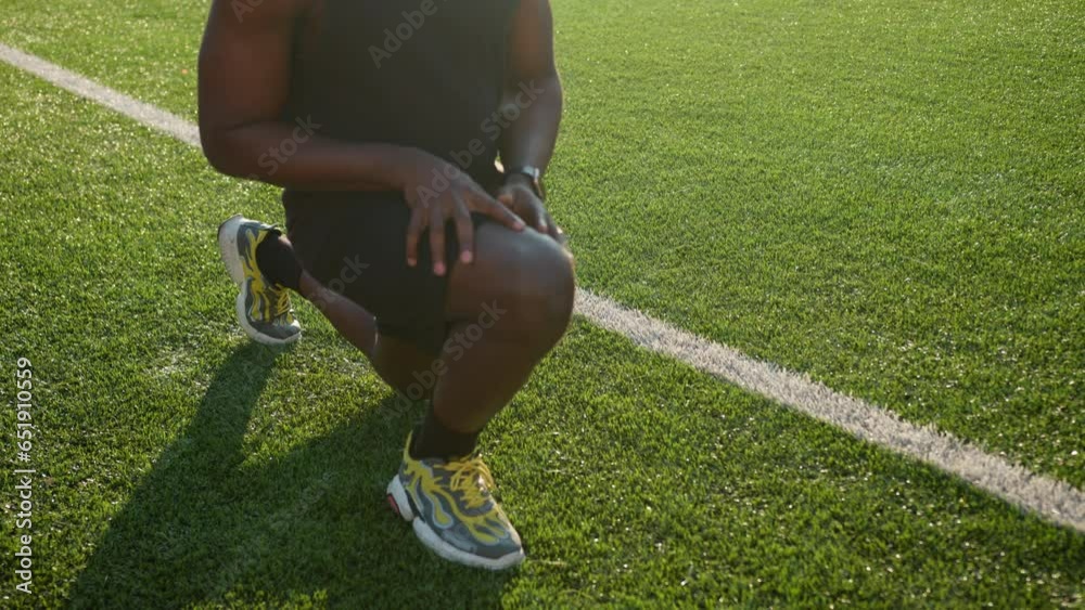 Strong sportsman African American athletic male footballer doing lunges ...