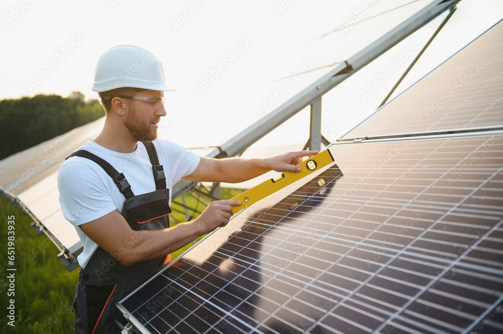 Foto de Side view of male worker installing solar modules and support ...